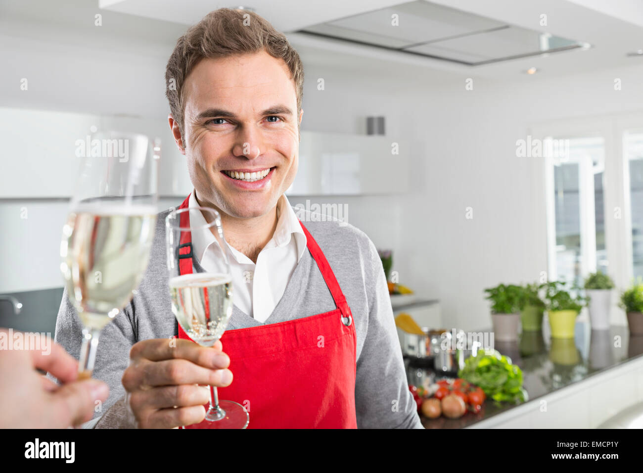 Portrait of smiling man toasting with glass of sparkling wine in ...