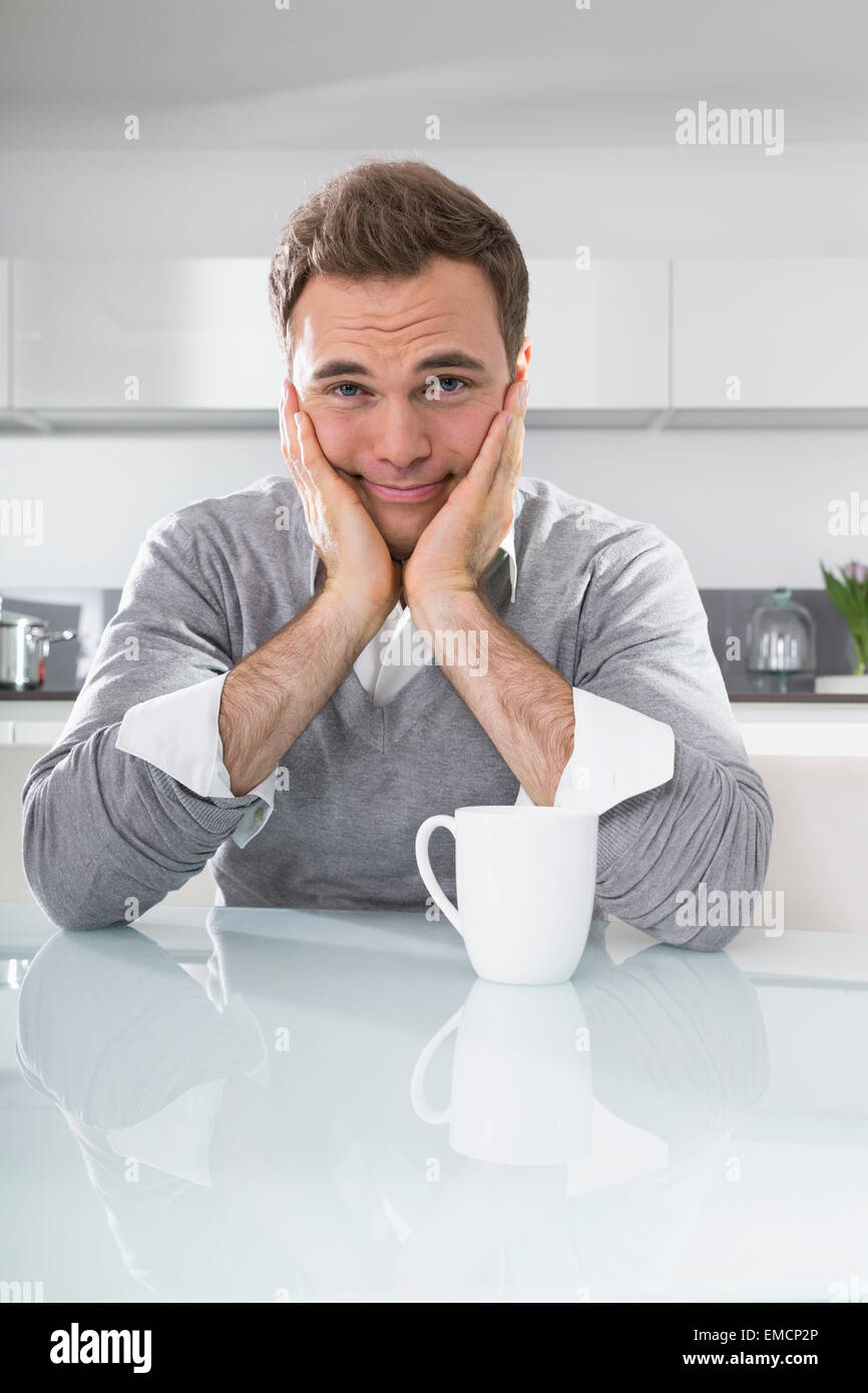 Portrait of man with head in his hands sitting at kitchen table Stock ...