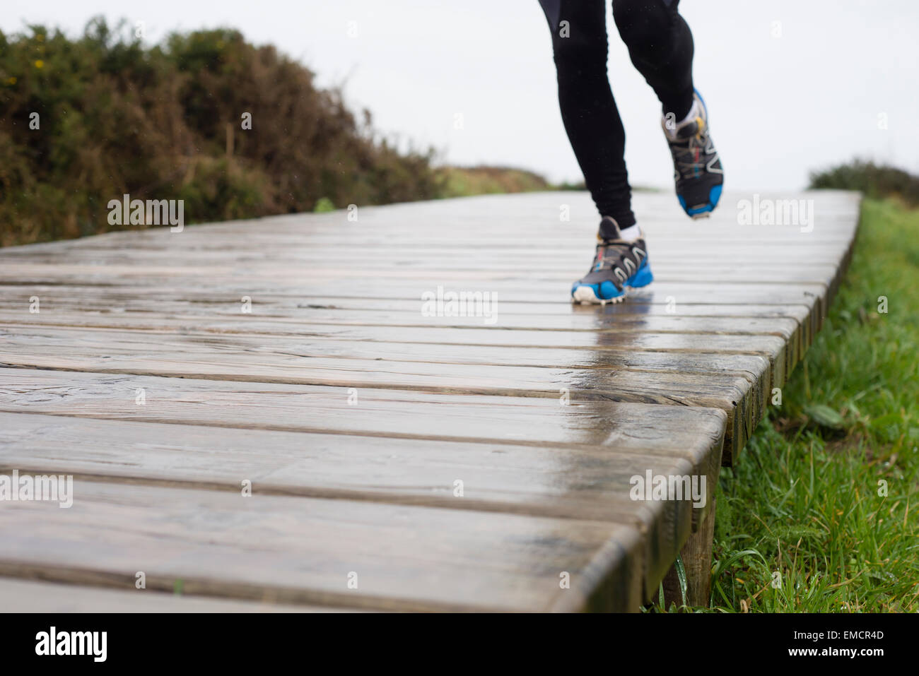 Jogger running on wet boardwalk Stock Photo - Alamy