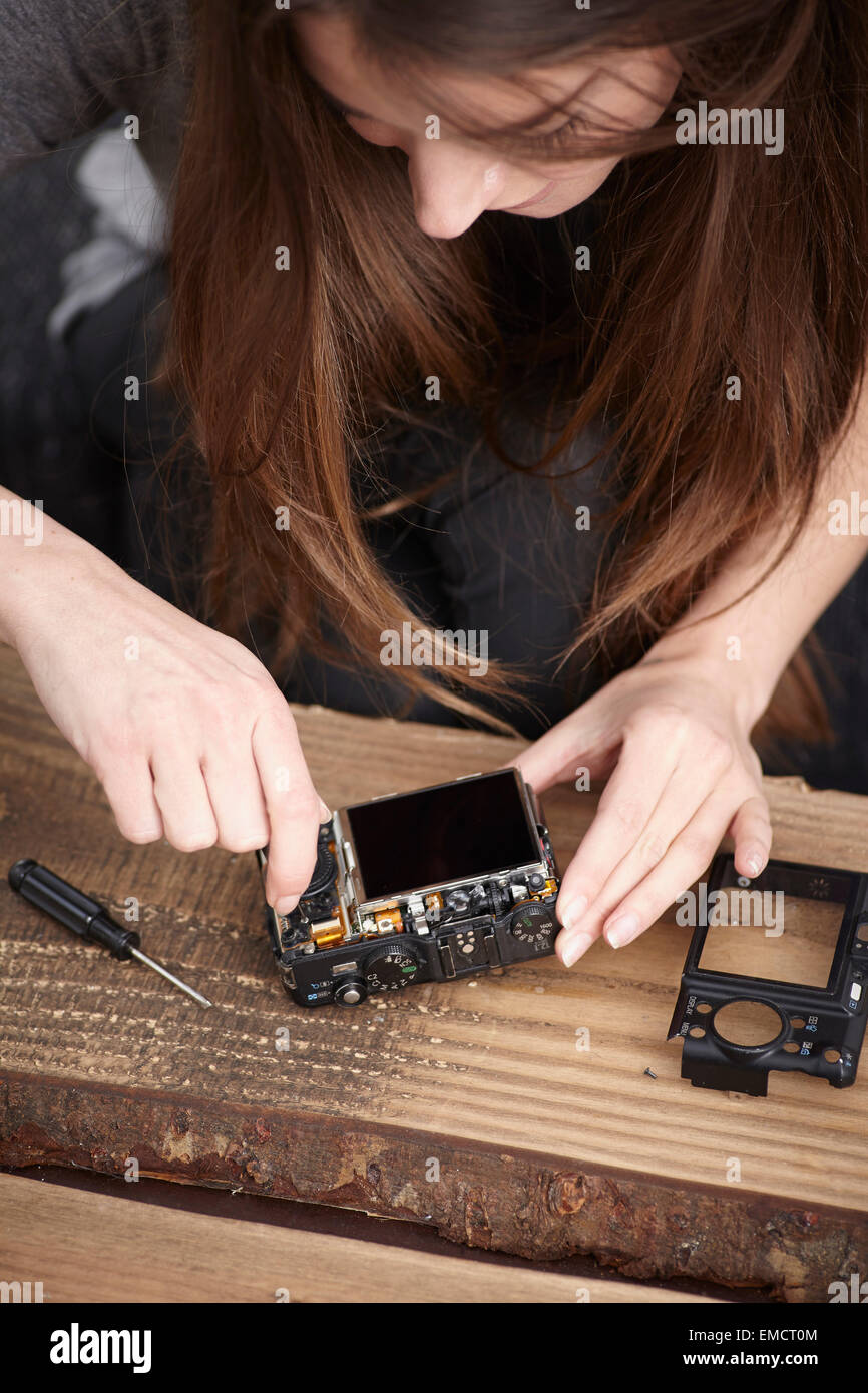 Young woman repairing camera Stock Photo - Alamy