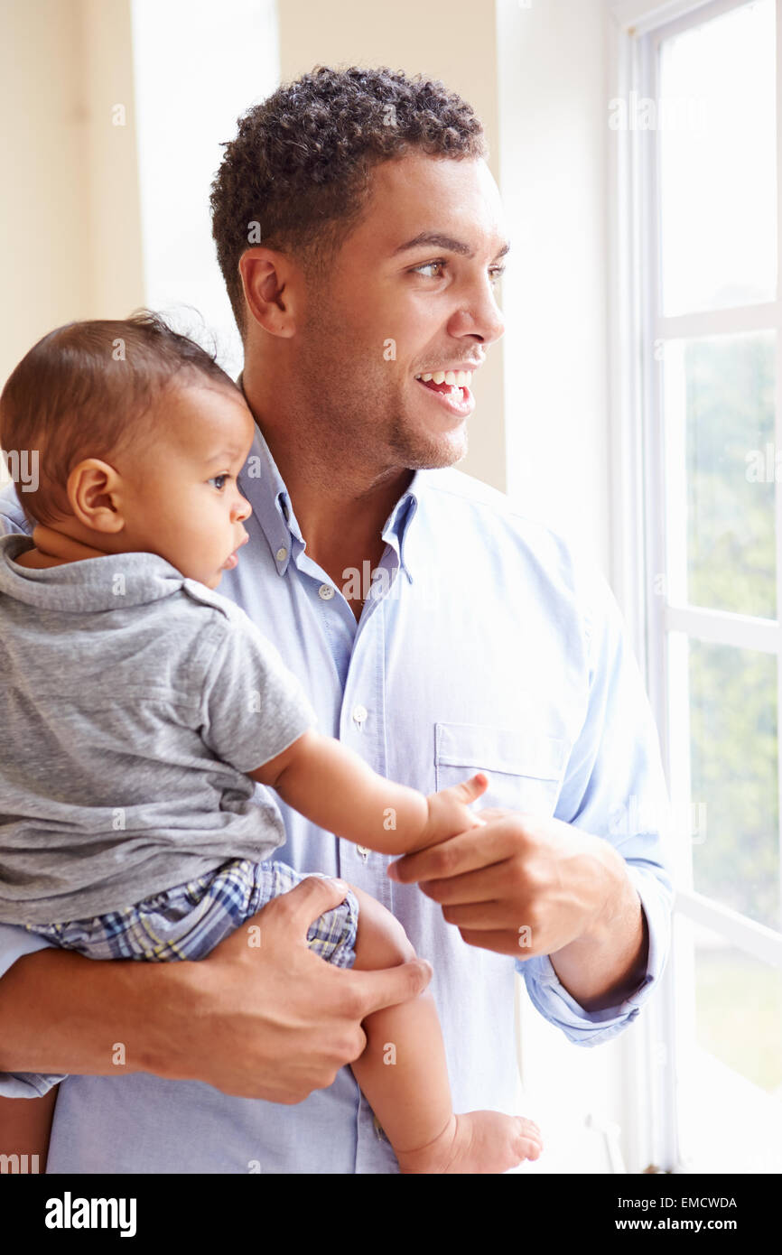 Smiling Father Standing By Window With Baby Son At Home Stock Photo - Alamy