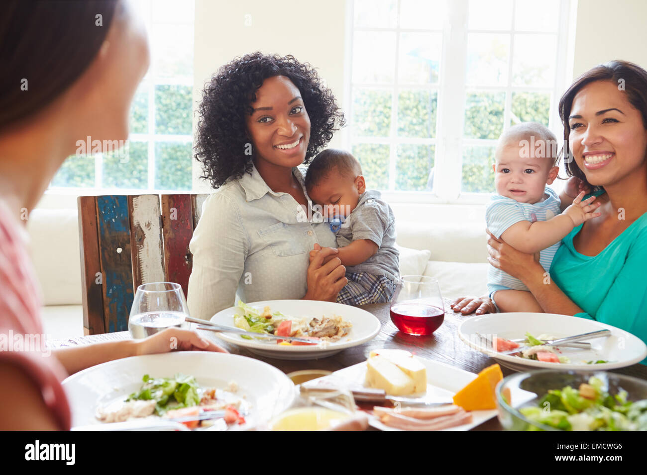 Female Friends With Babies Enjoying Meal At Home Together Stock Photo ...