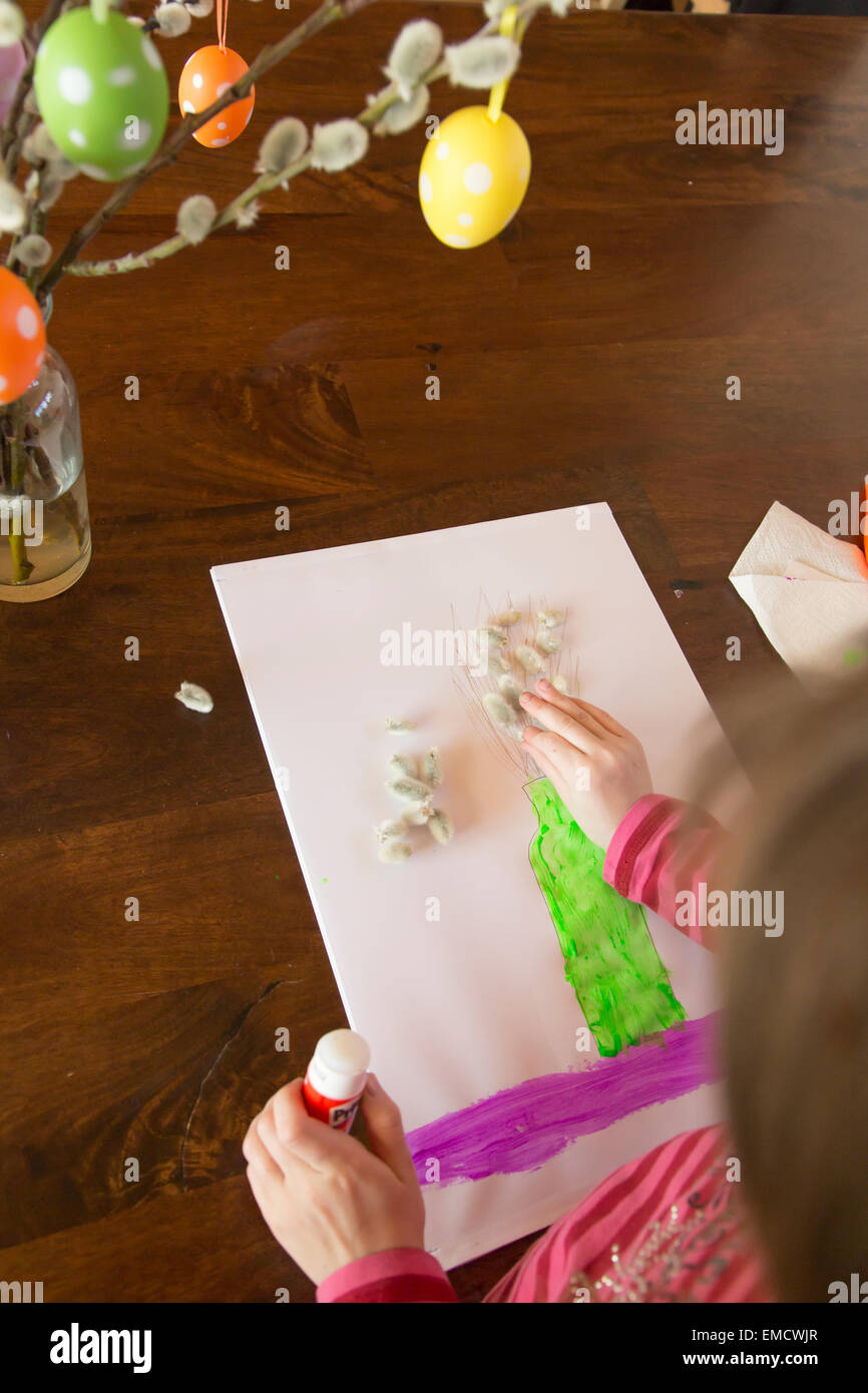 Girl working on Easter painting with glue stick Stock Photo - Alamy
