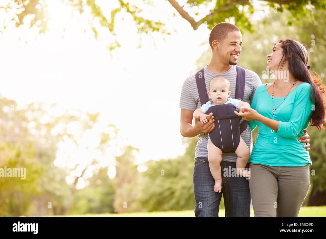 Family With Baby Son In Carrier Walking Through Park Stock Photo - Alamy