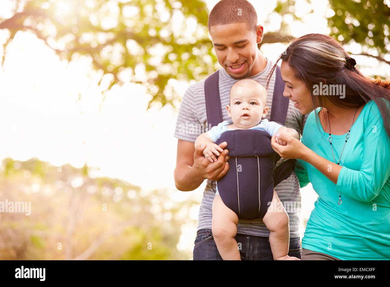 Family With Baby Son In Carrier Walking Through Park Stock Photo - Alamy