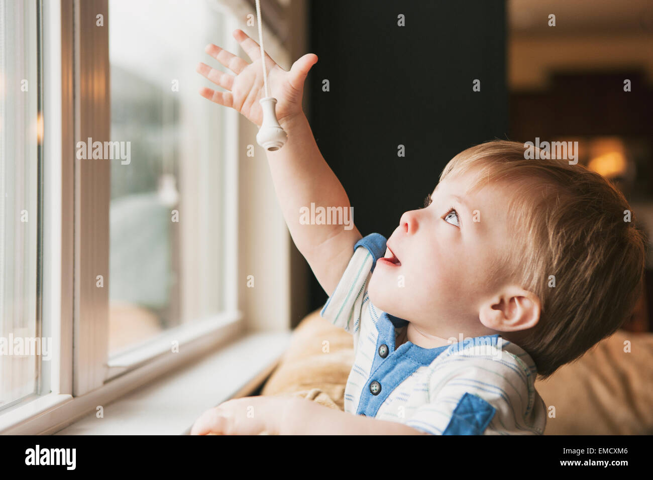 Little boy reaching out for window blind cord Stock Photo - Alamy