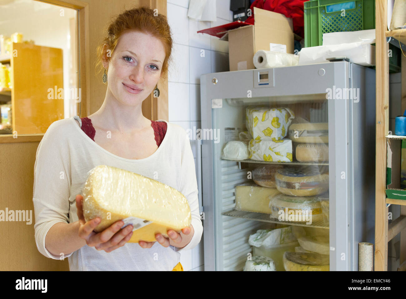 Portrait of smiling young woman in wholefood shop holding piece of ...