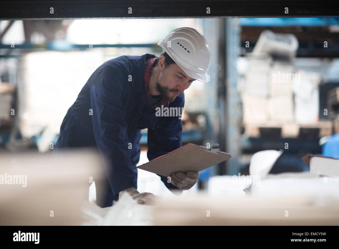 Warehouseman in storehouse holding clipboard Stock Photo - Alamy