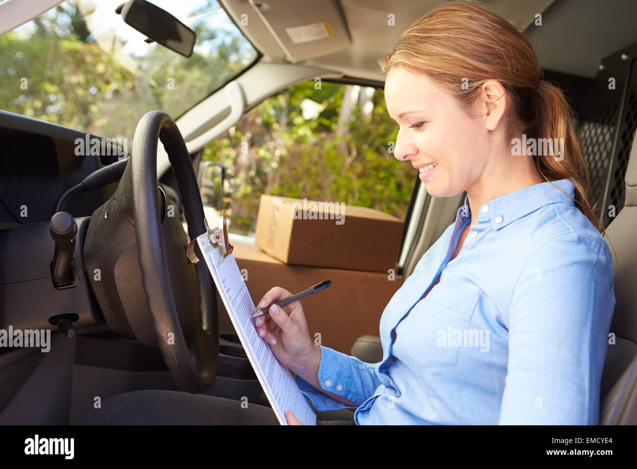 Female Delivery Driver Sitting In Van Filling Out Paperwork Stock Photo ...