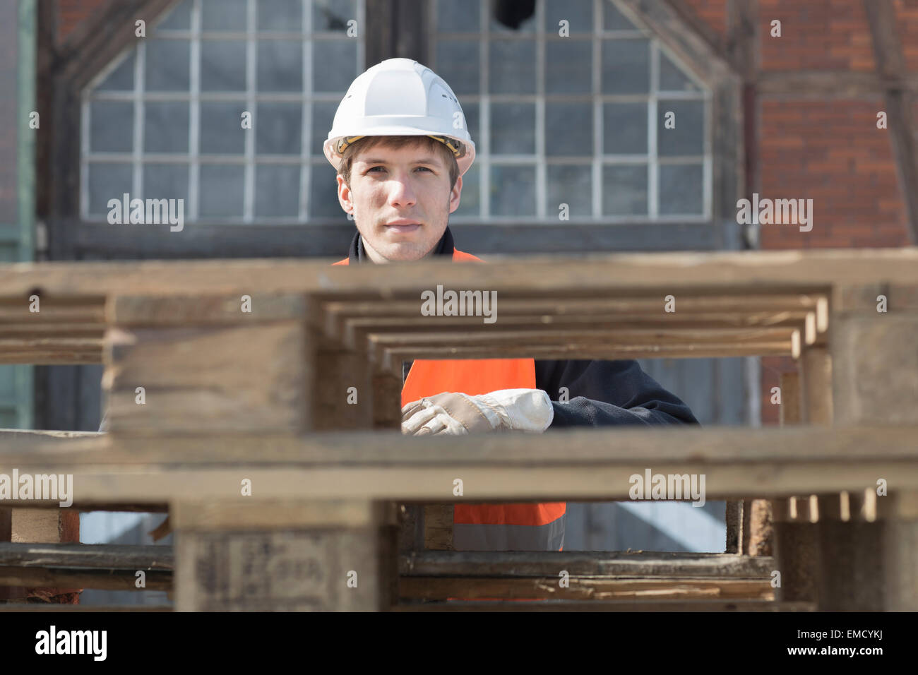 Construction worker standing behind pallets Stock Photo - Alamy