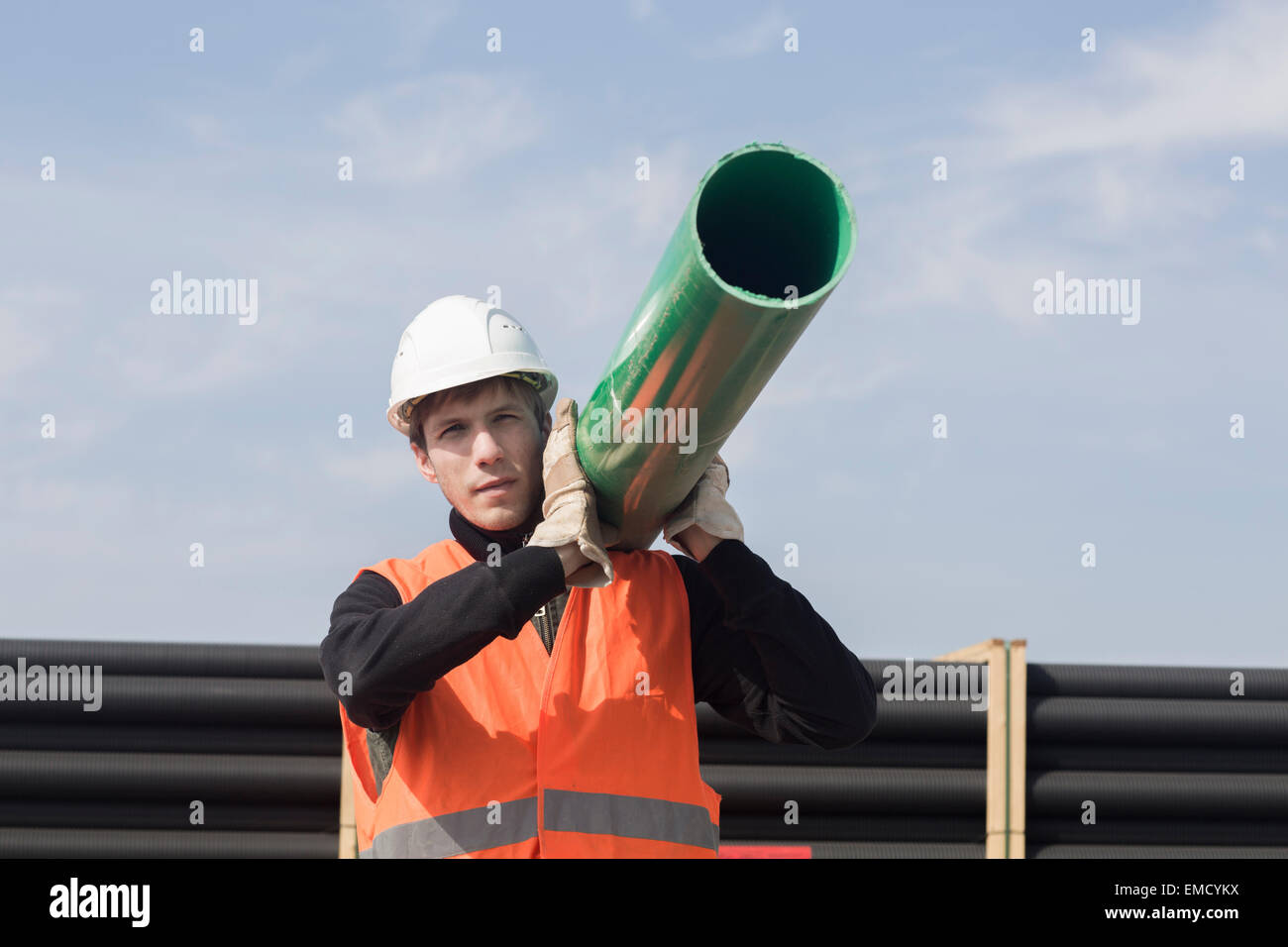 Construction worker carrying pipe on his shoulder Stock Photo - Alamy