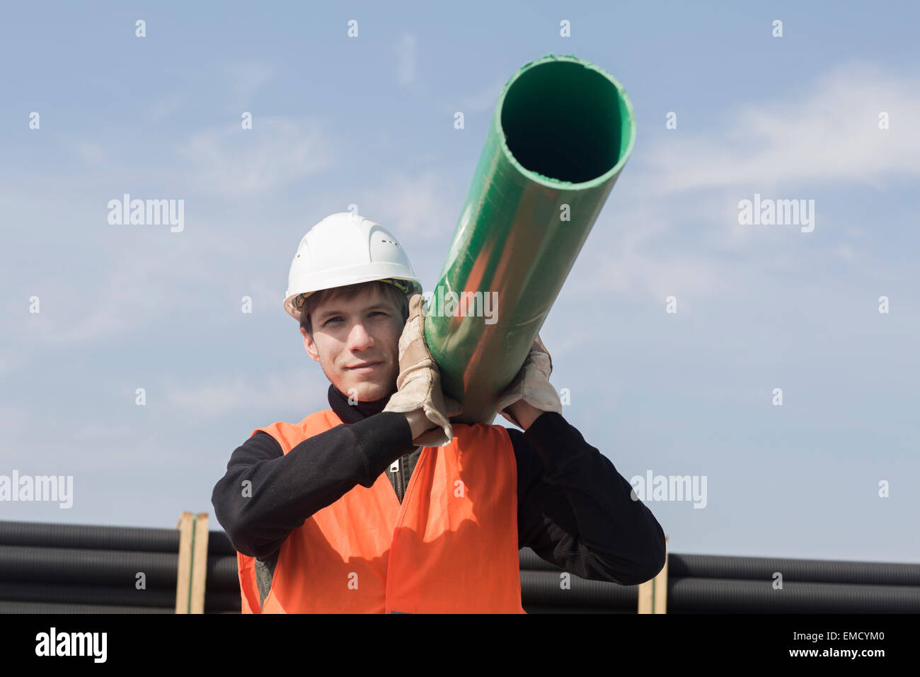 Construction worker carrying pipe on his shoulder Stock Photo - Alamy