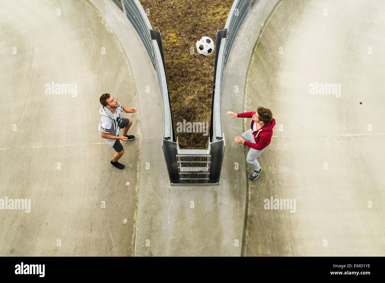 Two young men heading soccer ball over fence Stock Photo - Alamy