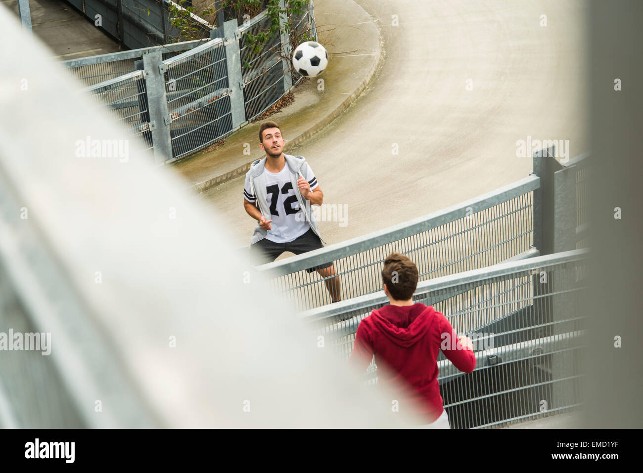Two young men heading soccer ball over fence Stock Photo - Alamy