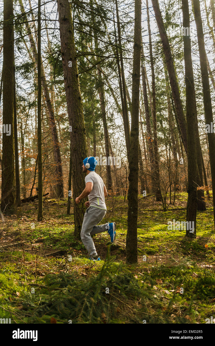 Young man jogging on forest path Stock Photo - Alamy