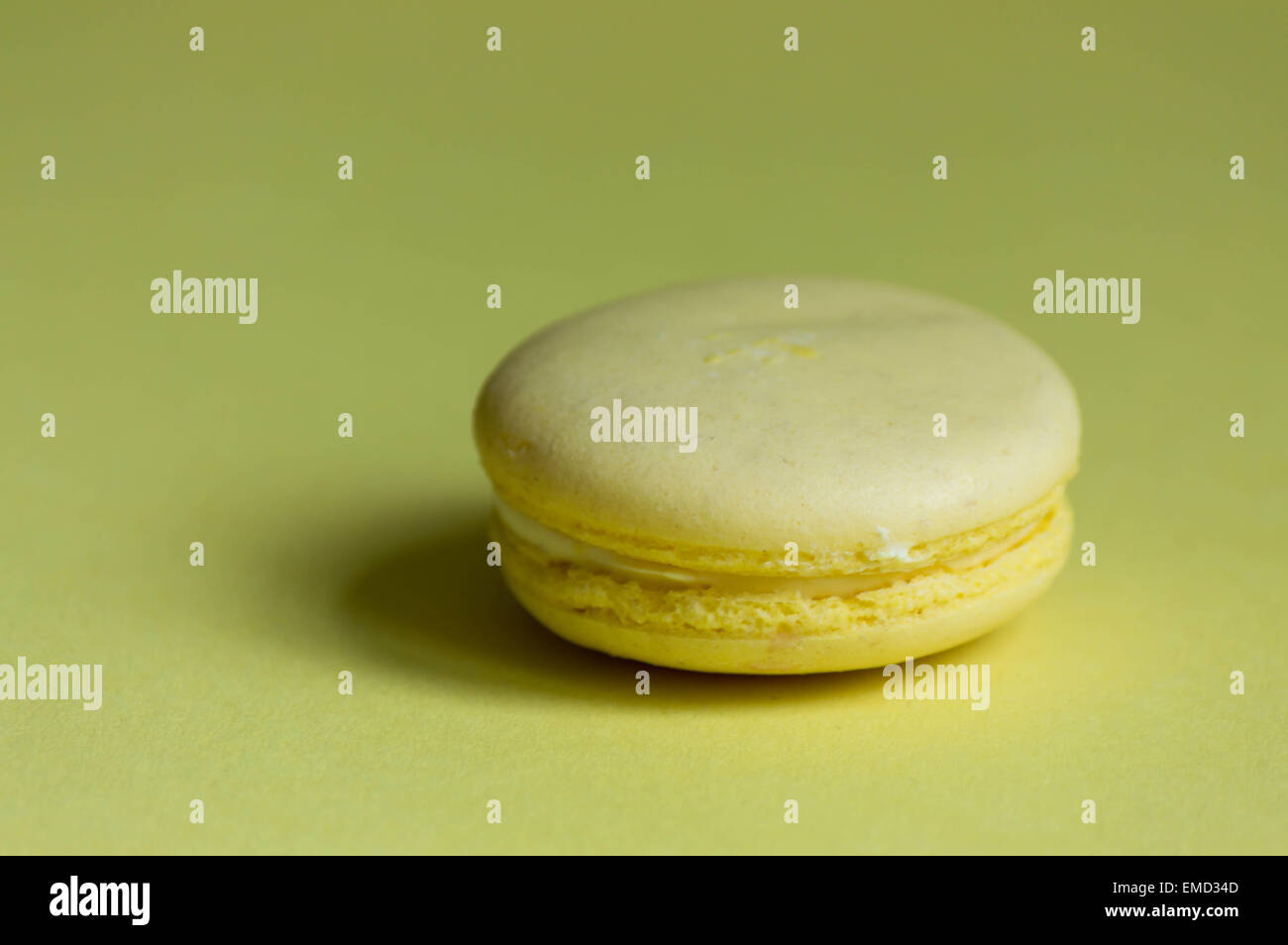 One Yellow lemon macaroon on yellow background Stock Photo - Alamy