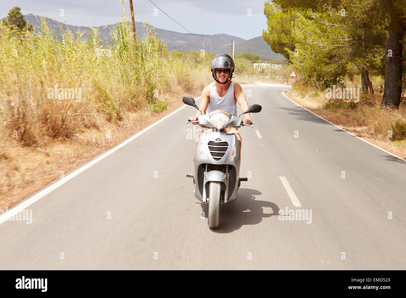 Young Man Riding Motor Scooter Along Country Road Stock Photo - Alamy