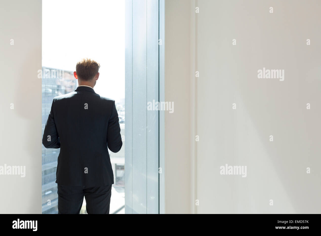 Businessman looking out of window Stock Photo - Alamy