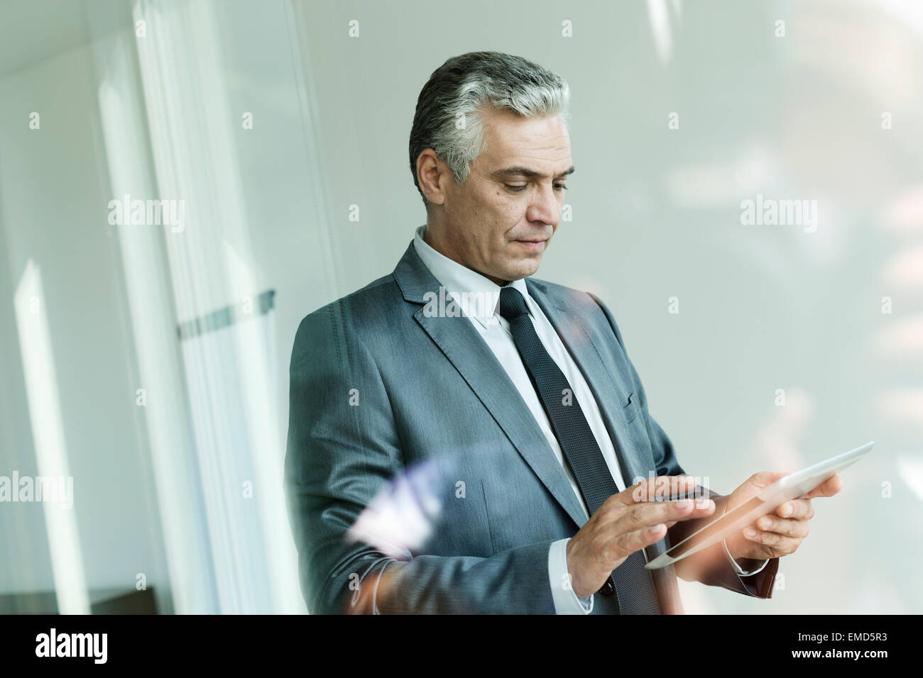 Businessman holding digital tablet, looking down Stock Photo - Alamy