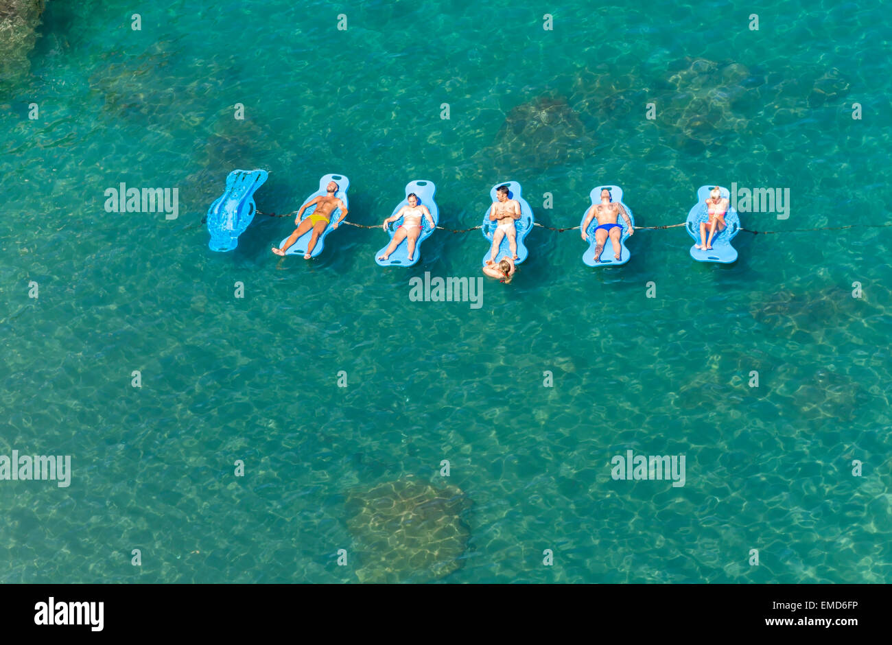 Swimmers sunbathing on body shaped floats. Safely relaxing in the ...