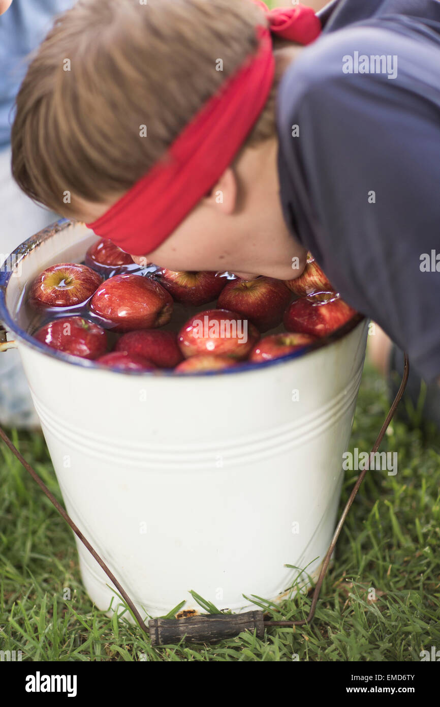 Blindfolded boy trying to take apple out of bucket with water Stock ...