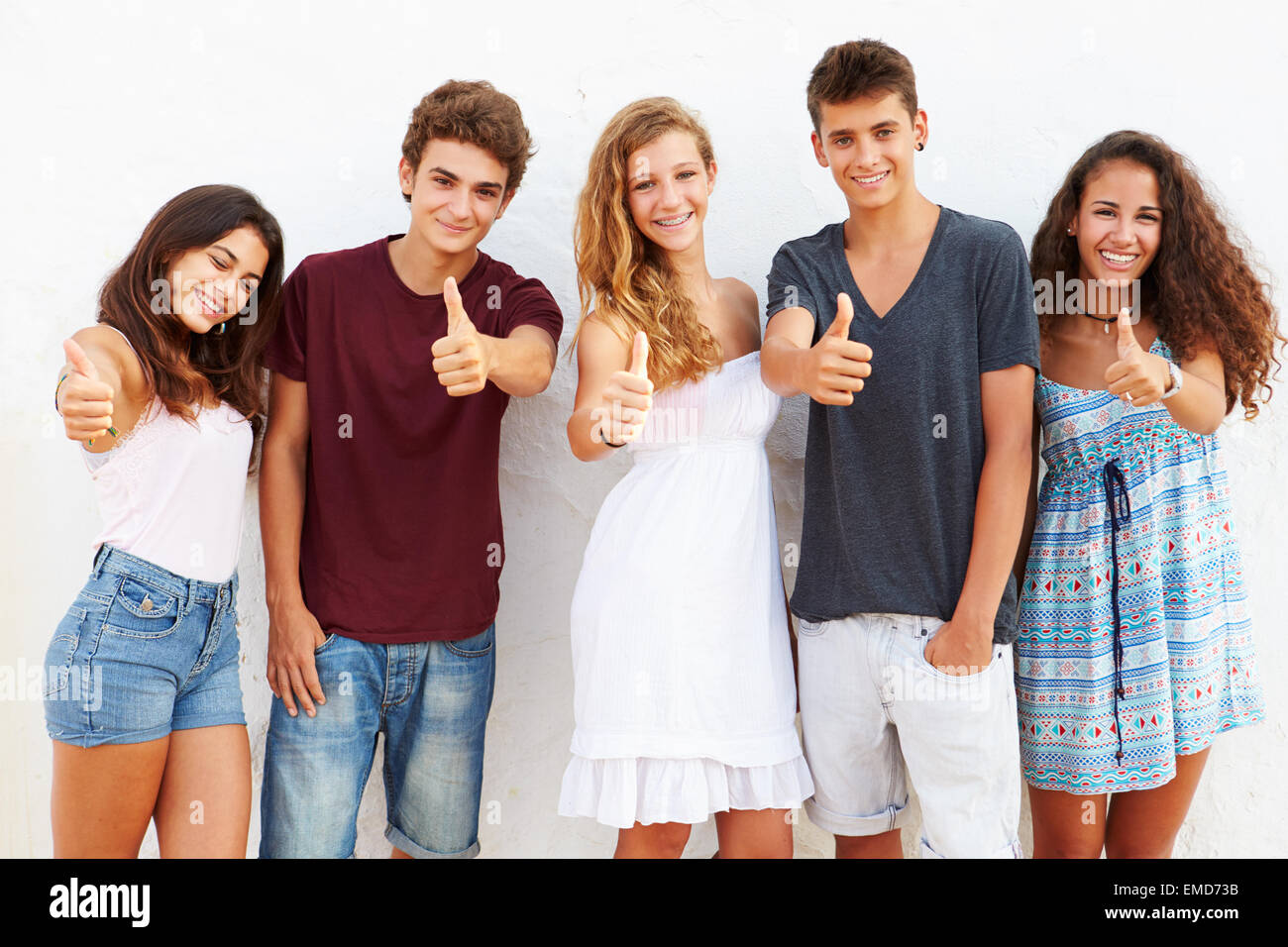 Teenage Group Leaning Against Wall Giving Thumbs Up Stock Photo - Alamy