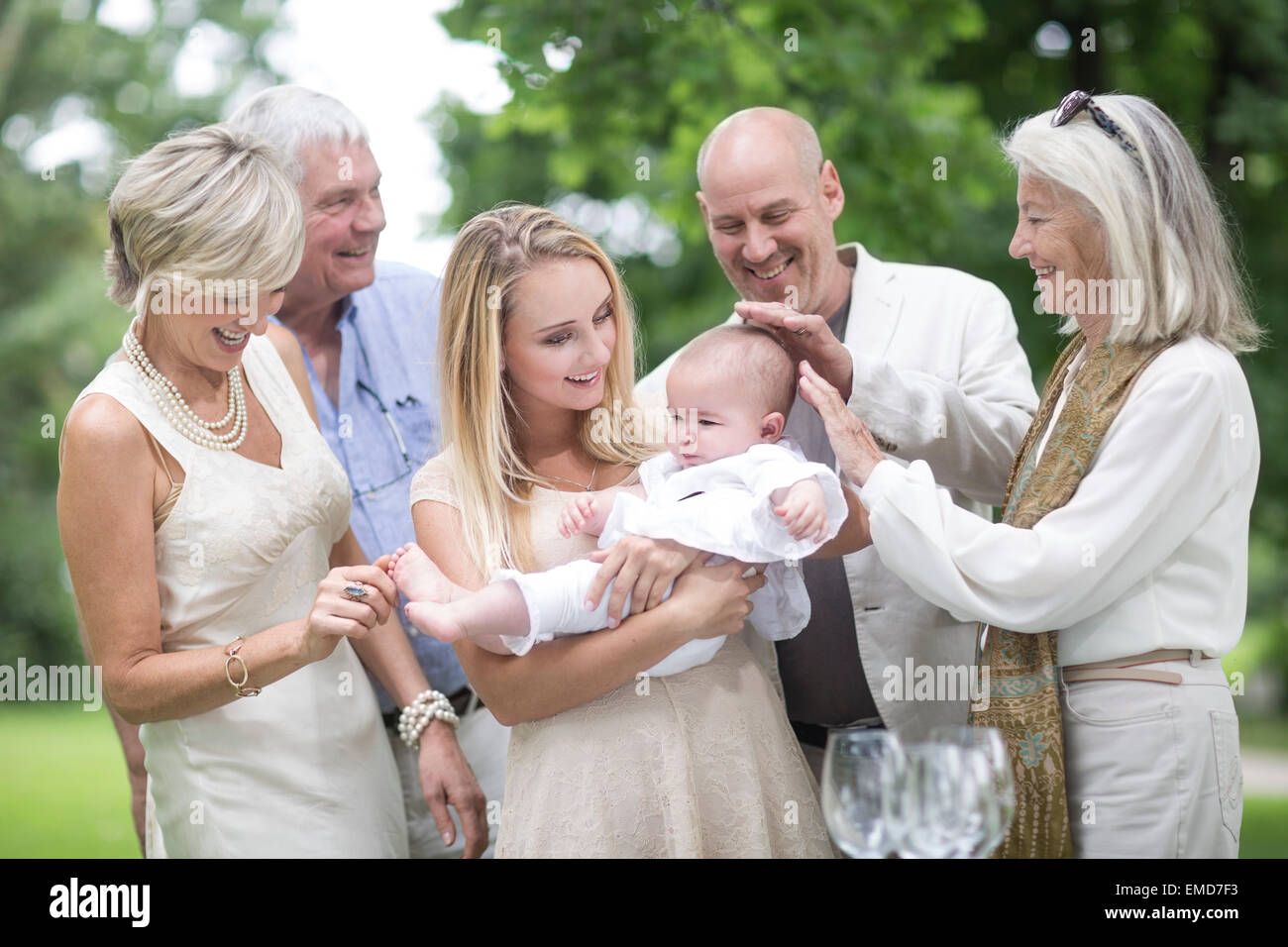 Family gathering around baby outdoors Stock Photo - Alamy