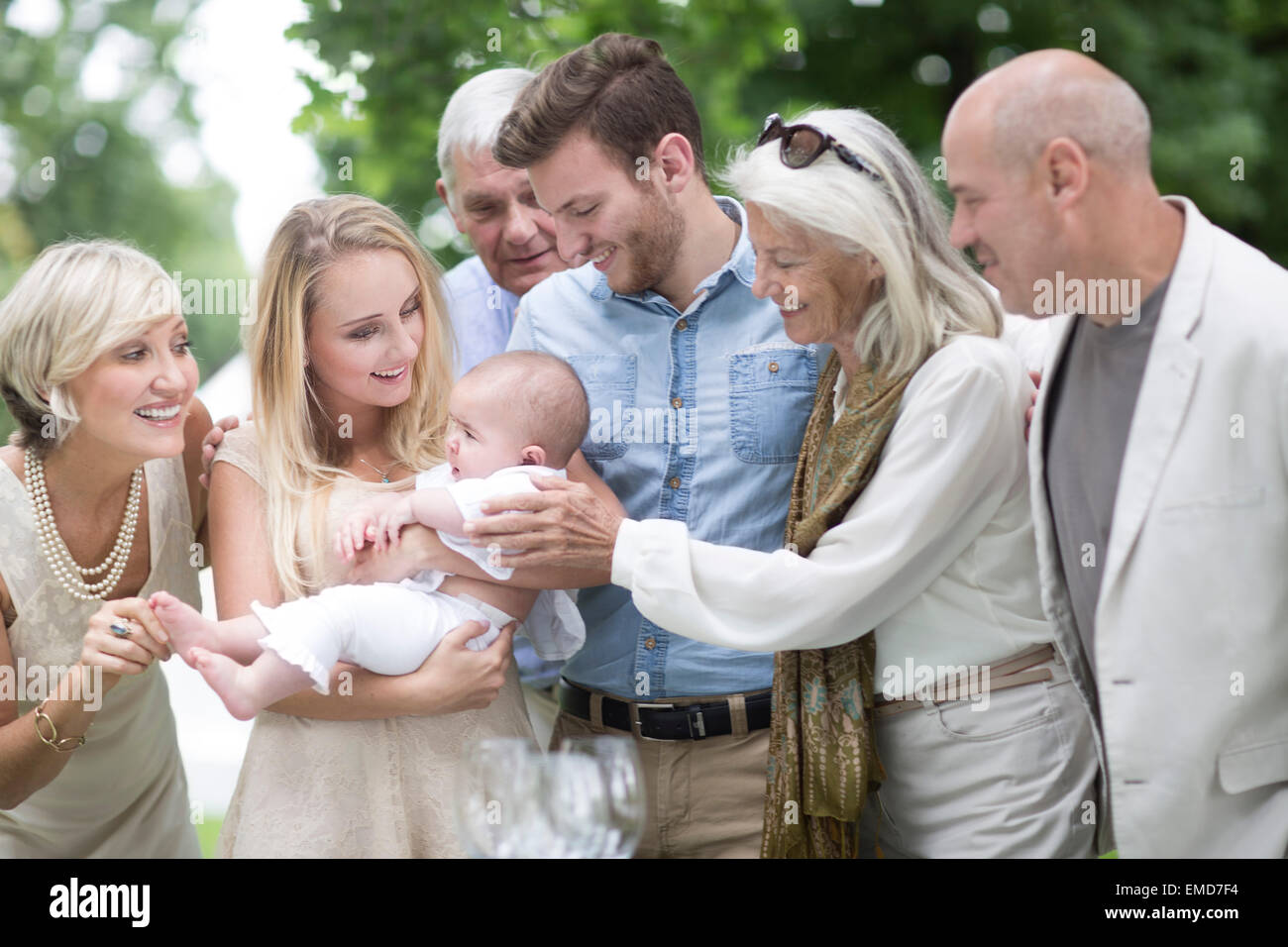 Family gathering around baby outdoors Stock Photo - Alamy
