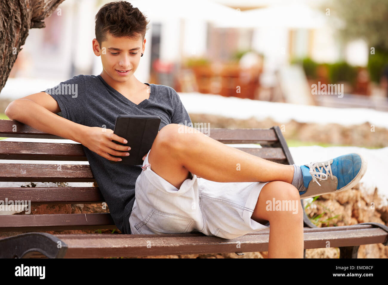 Teenage Boy On Park Bench Using Digital Tablet Stock Photo - Alamy