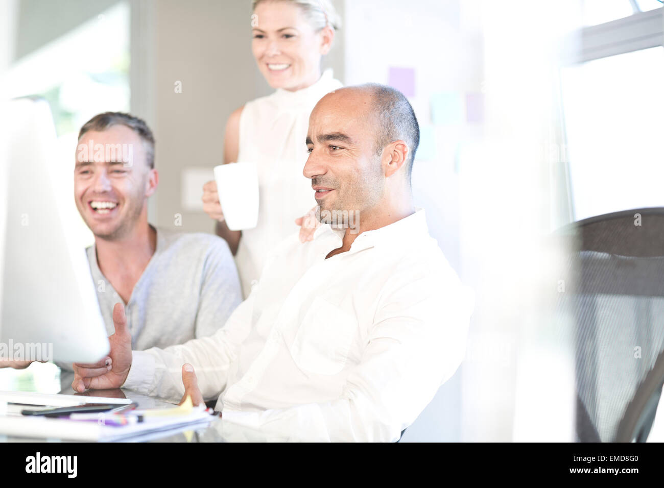 Three colleagues looking at screen in an office Stock Photo - Alamy
