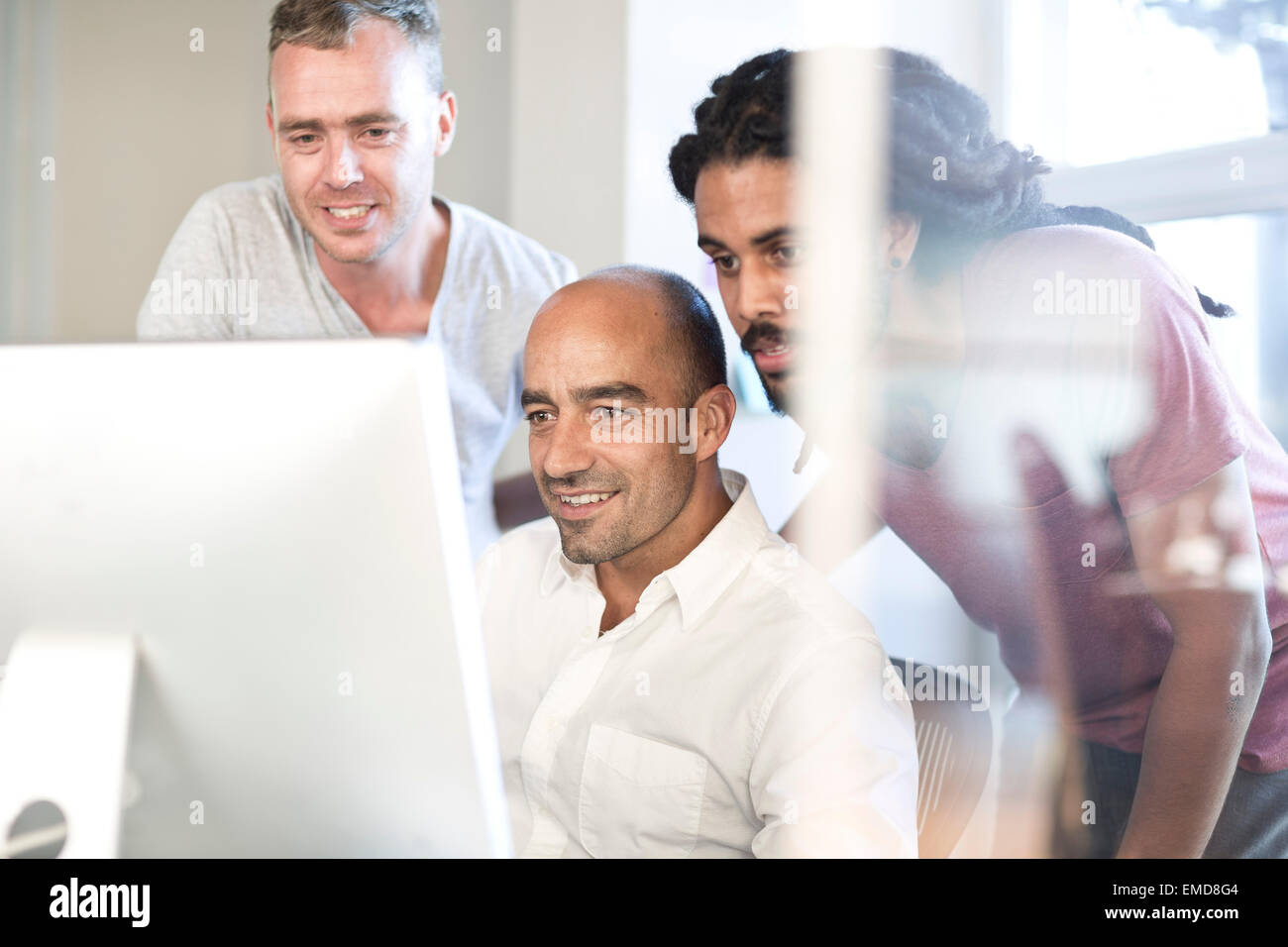 Three colleagues looking at screen in an office Stock Photo - Alamy
