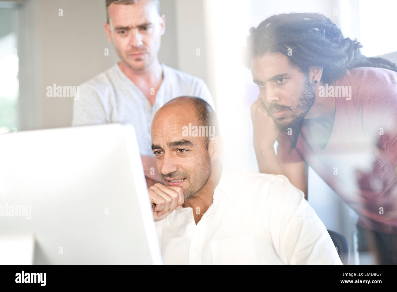 Three colleagues looking at screen in an office Stock Photo - Alamy