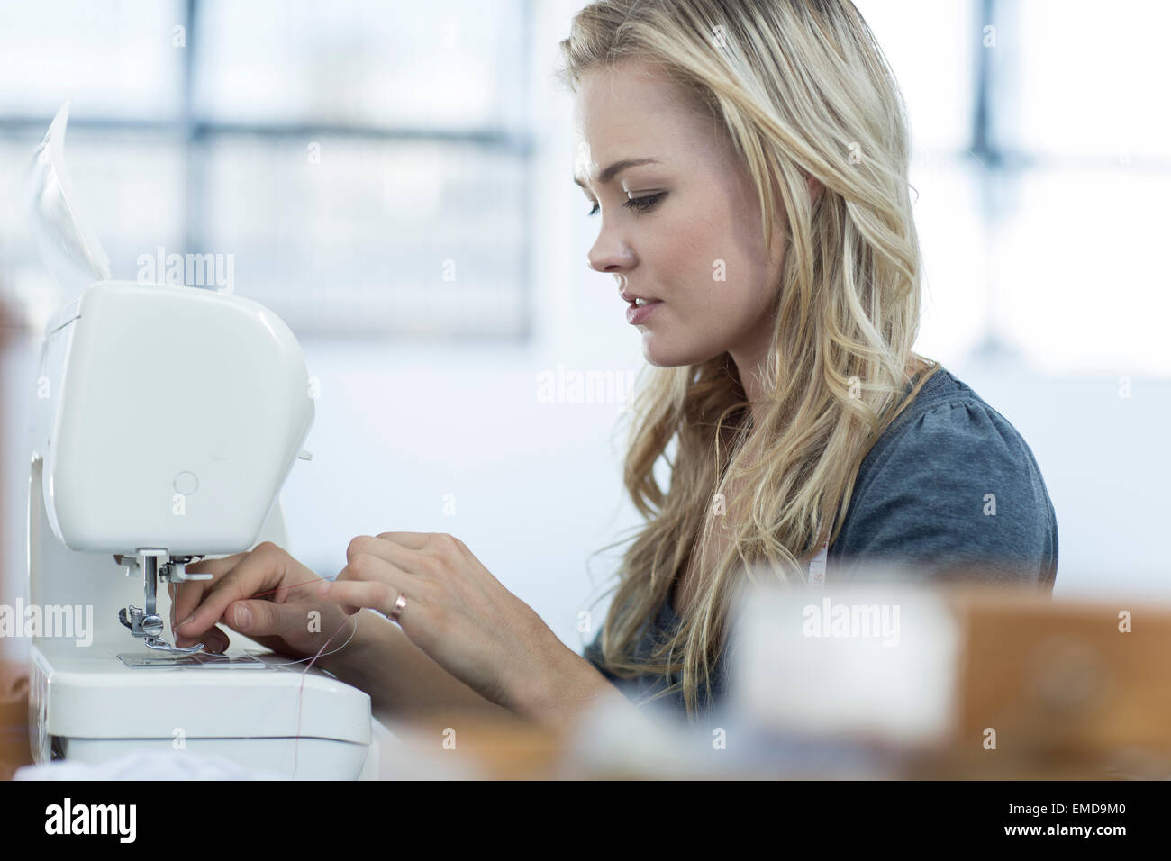 Young woman putting thread into a sewing machine Stock Photo - Alamy