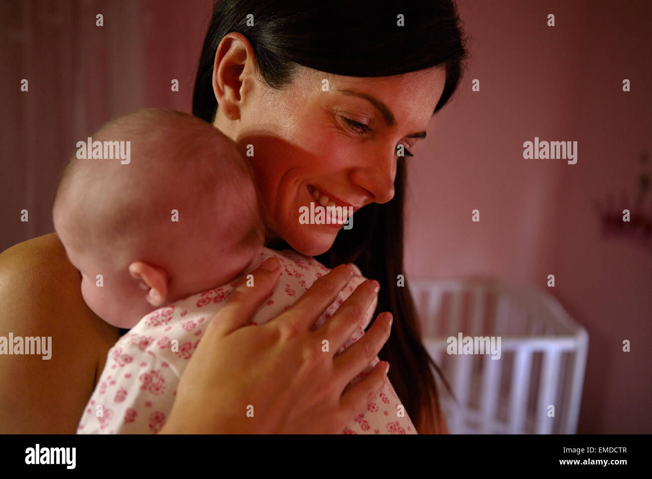 Mother At Home Cuddling Newborn Baby In Nursery Stock Photo - Alamy