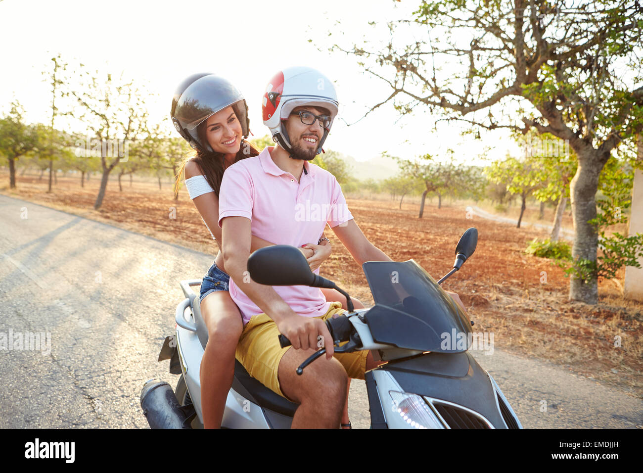 Young Couple Riding Motor Scooter Along Country Road Stock Photo - Alamy