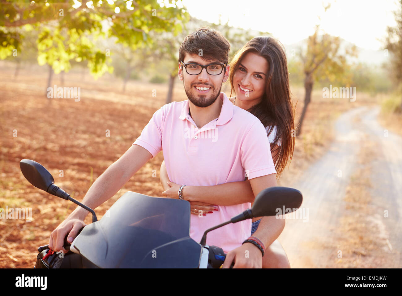 Young Couple Riding Motor Scooter Along Country Road Stock Photo - Alamy