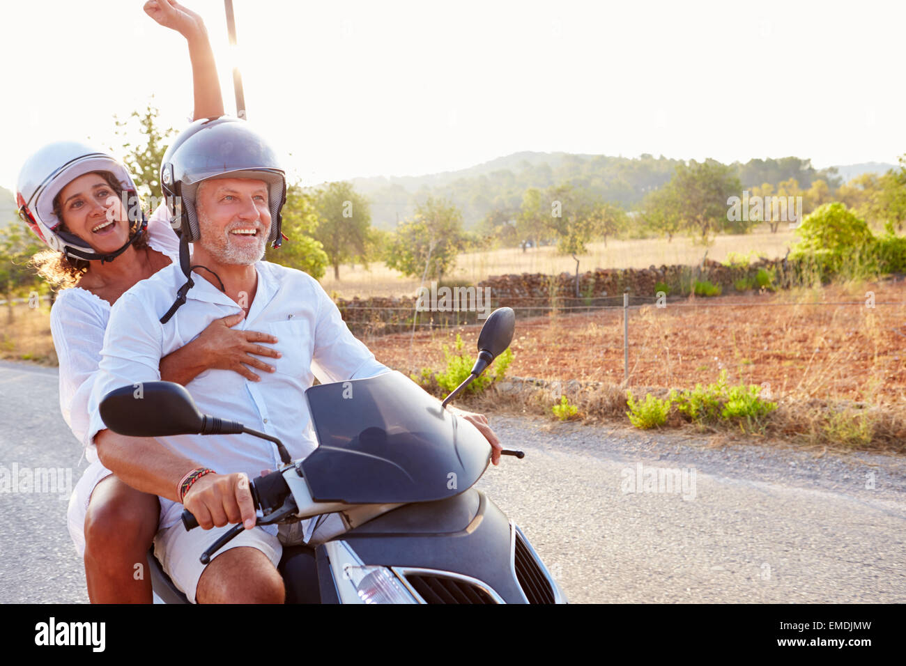 Mature Couple Riding Motor Scooter Along Country Road Stock Photo - Alamy