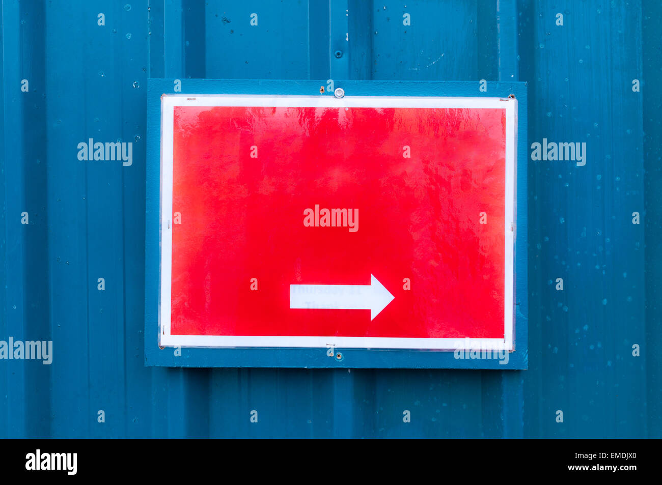 Reflective red notice board with an arrow mounted on metal background ...
