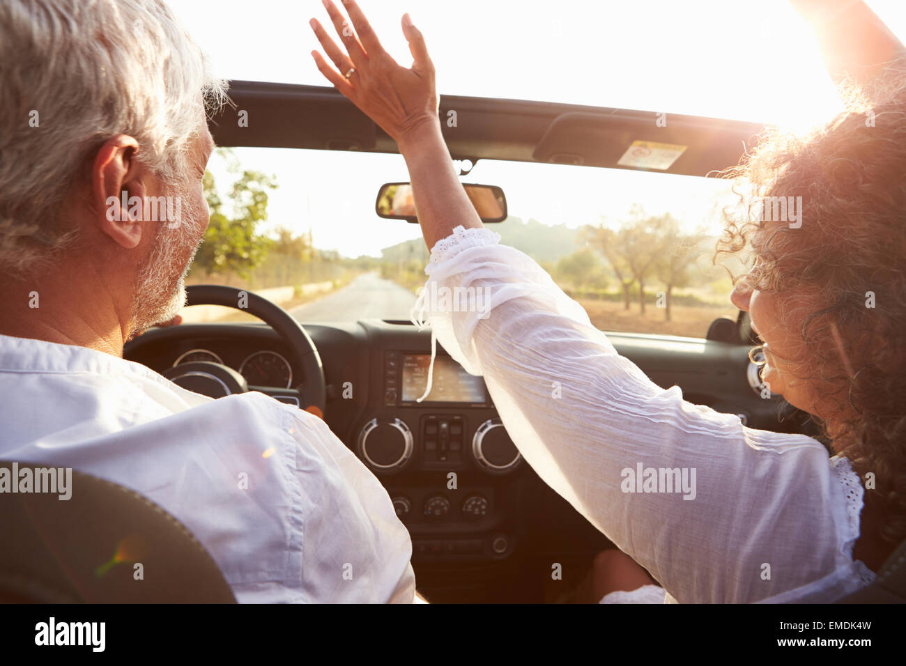Mature Couple Driving Along Country Road In Open Top Car Stock Photo ...