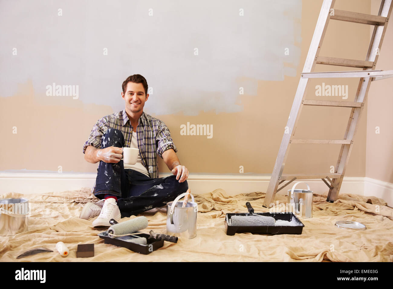 Man Taking A Break Whilst Decorating Room Stock Photo - Alamy