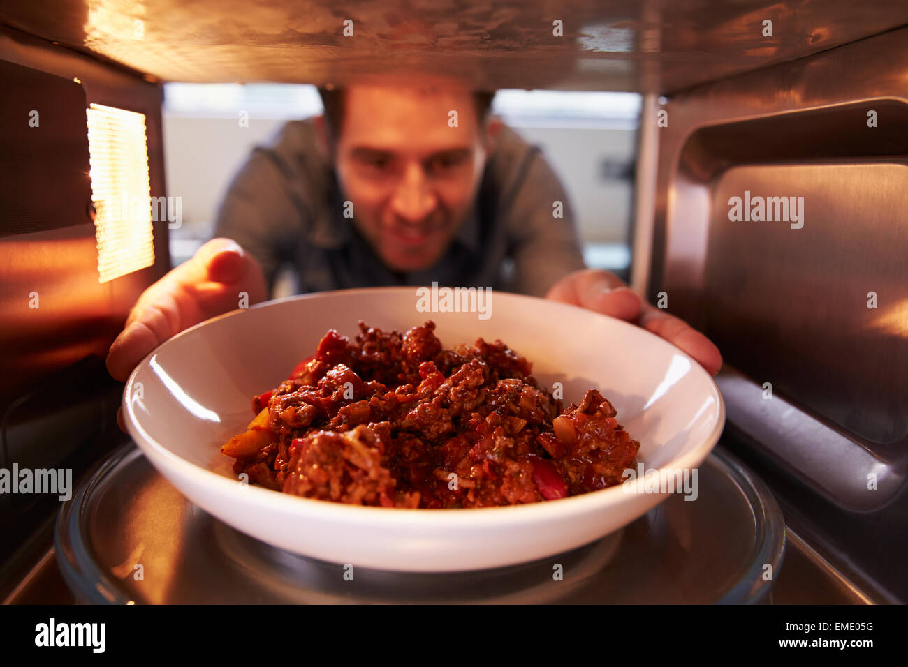 Man Putting Leftover Chili Into Microwave Oven To Cook Stock Photo - Alamy