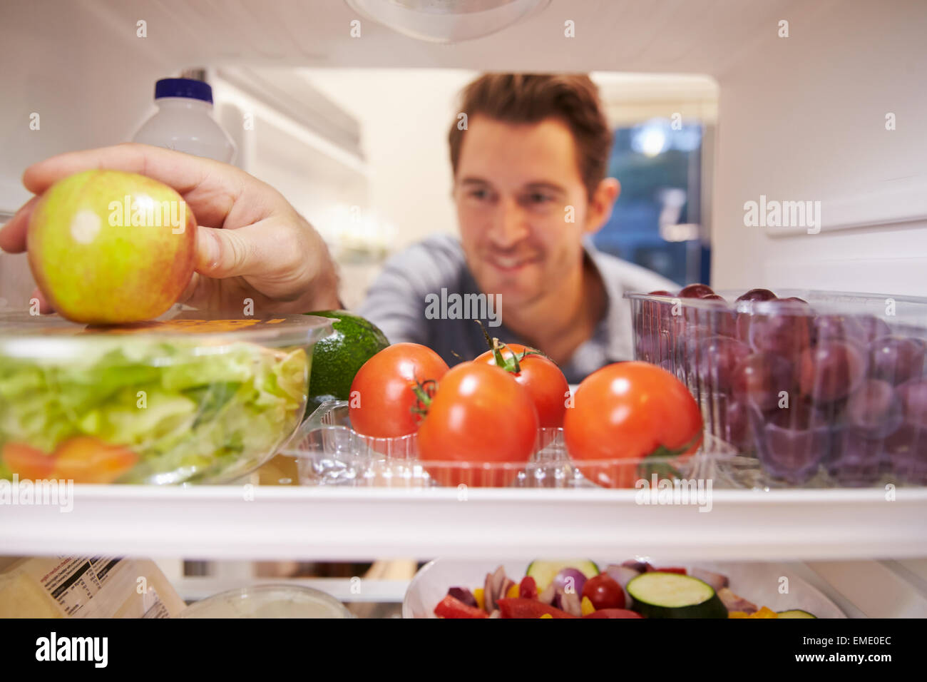 Man Looking Inside Fridge Full Of Food And Choosing Apple Stock Photo ...