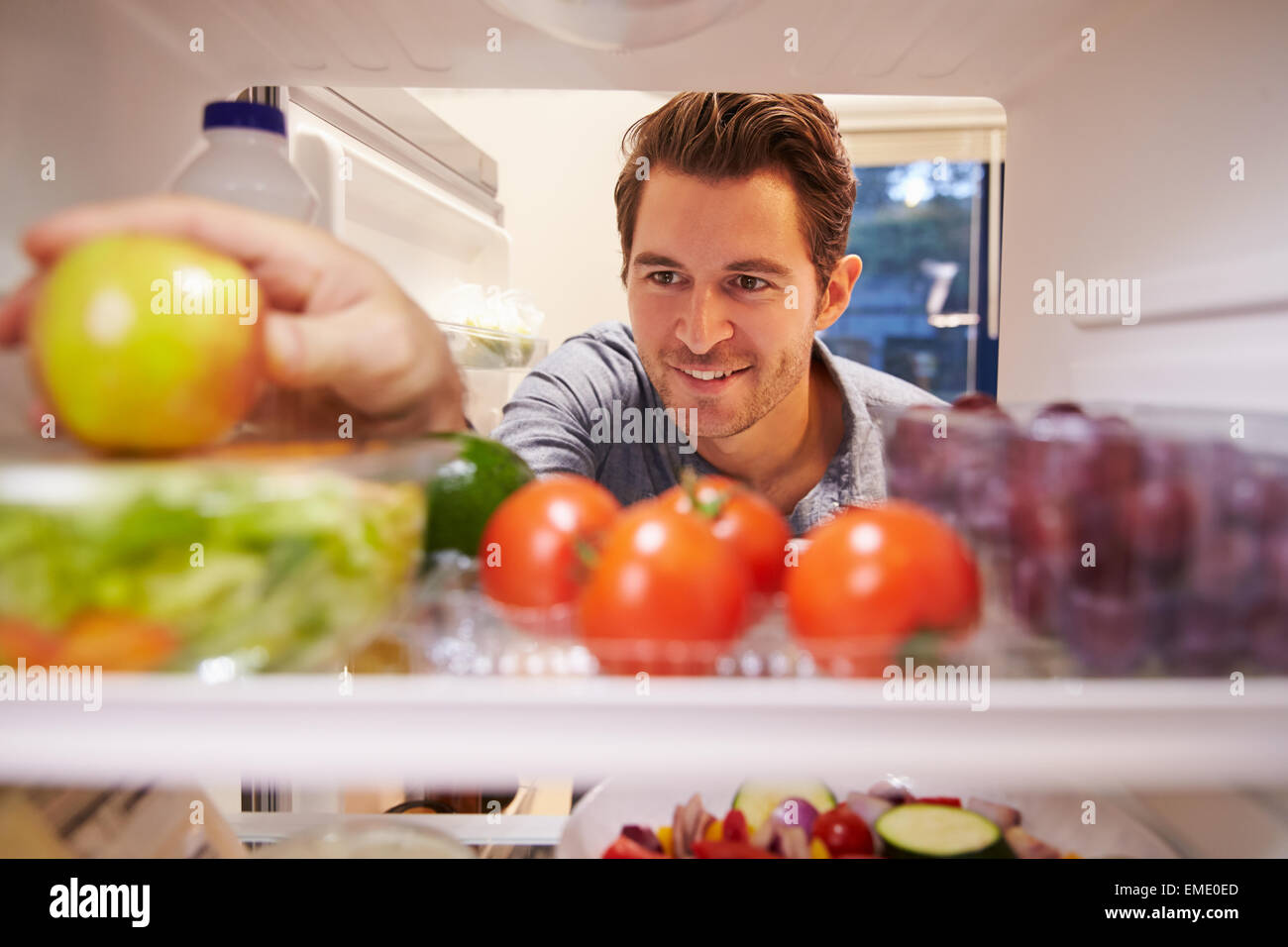 Man Looking Inside Fridge Full Of Food And Choosing Apple Stock Photo ...