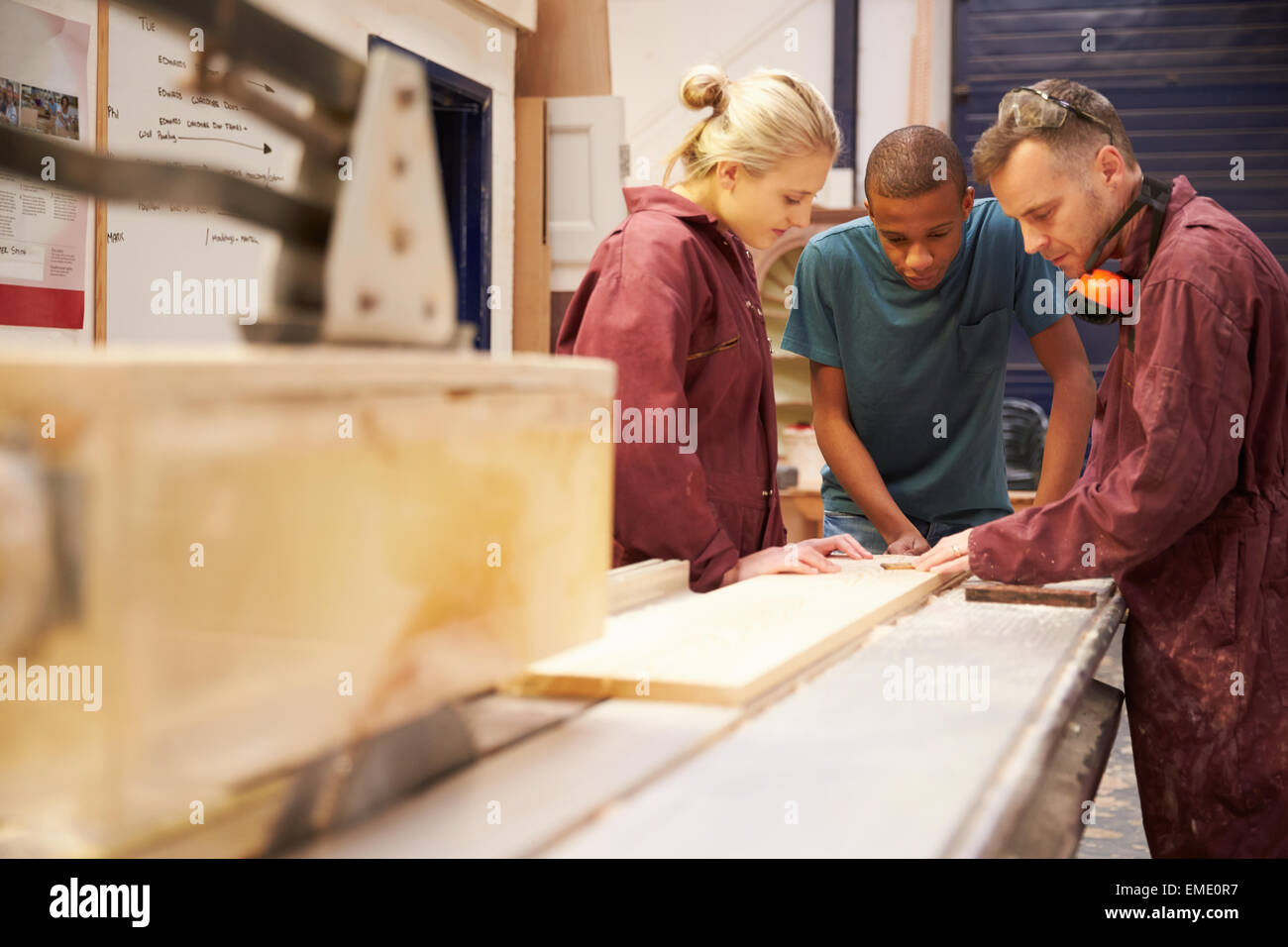 Carpenter With Apprentices Using Circular Saw In Workshop Stock Photo ...