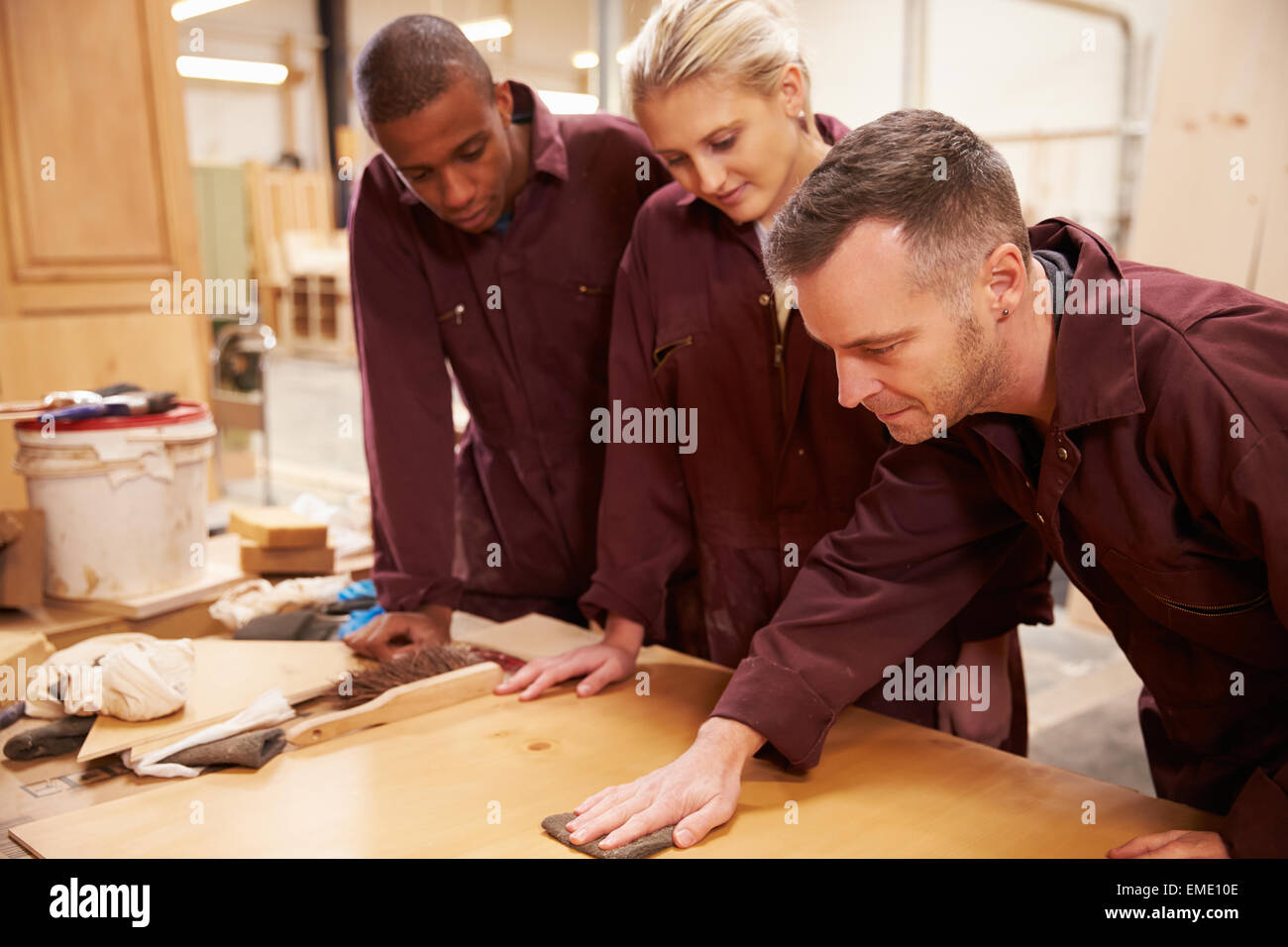 Carpenter With Apprentices Finishing Wood In Workshop Stock Photo - Alamy