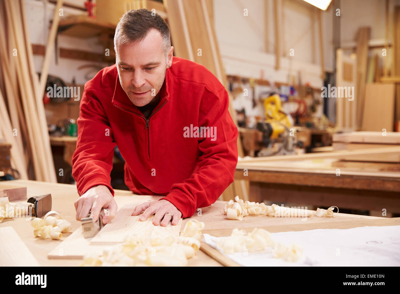 Carpenter Planing Wood In Workshop Stock Photo - Alamy
