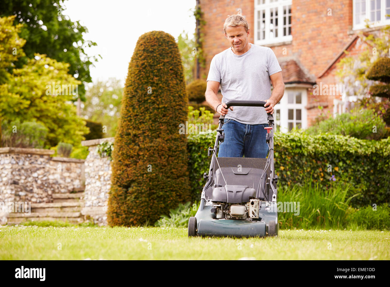 Man Working In Garden Cutting Grass With Lawn Mower Stock Photo - Alamy