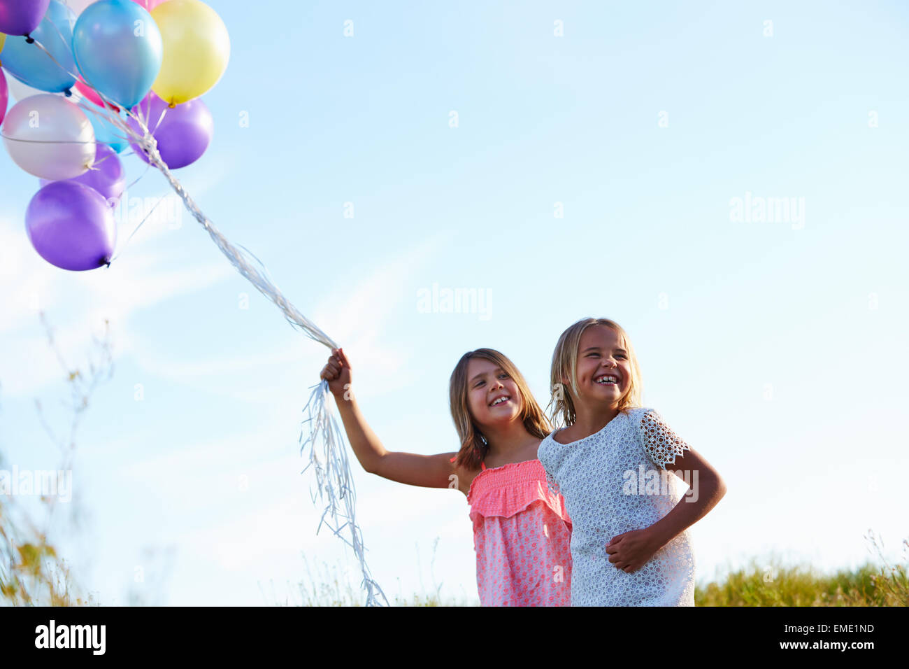 Two Young Girls Holding Bunch Of Colorful Balloons Outdoors Stock Photo ...