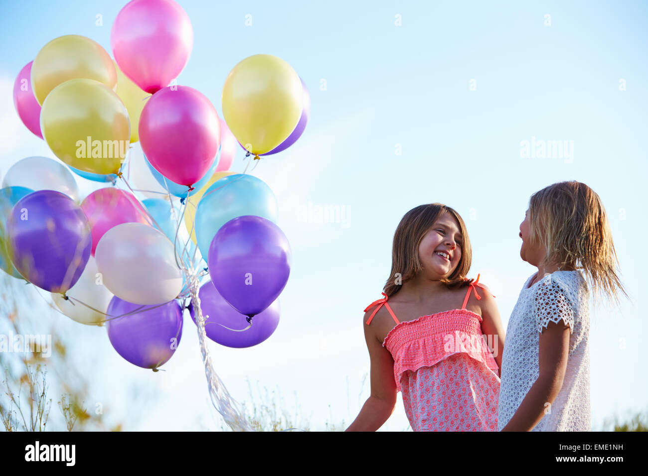Two Young Girls Holding Bunch Of Colorful Balloons Outdoors Stock Photo ...