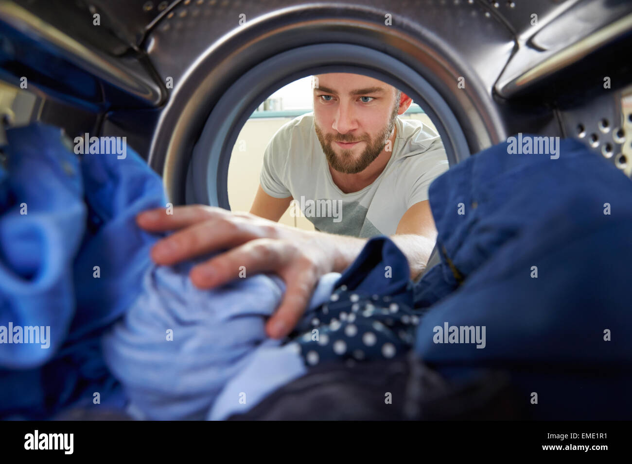 Man Doing Laundry Reaching Inside Washing Machine Stock Photo - Alamy